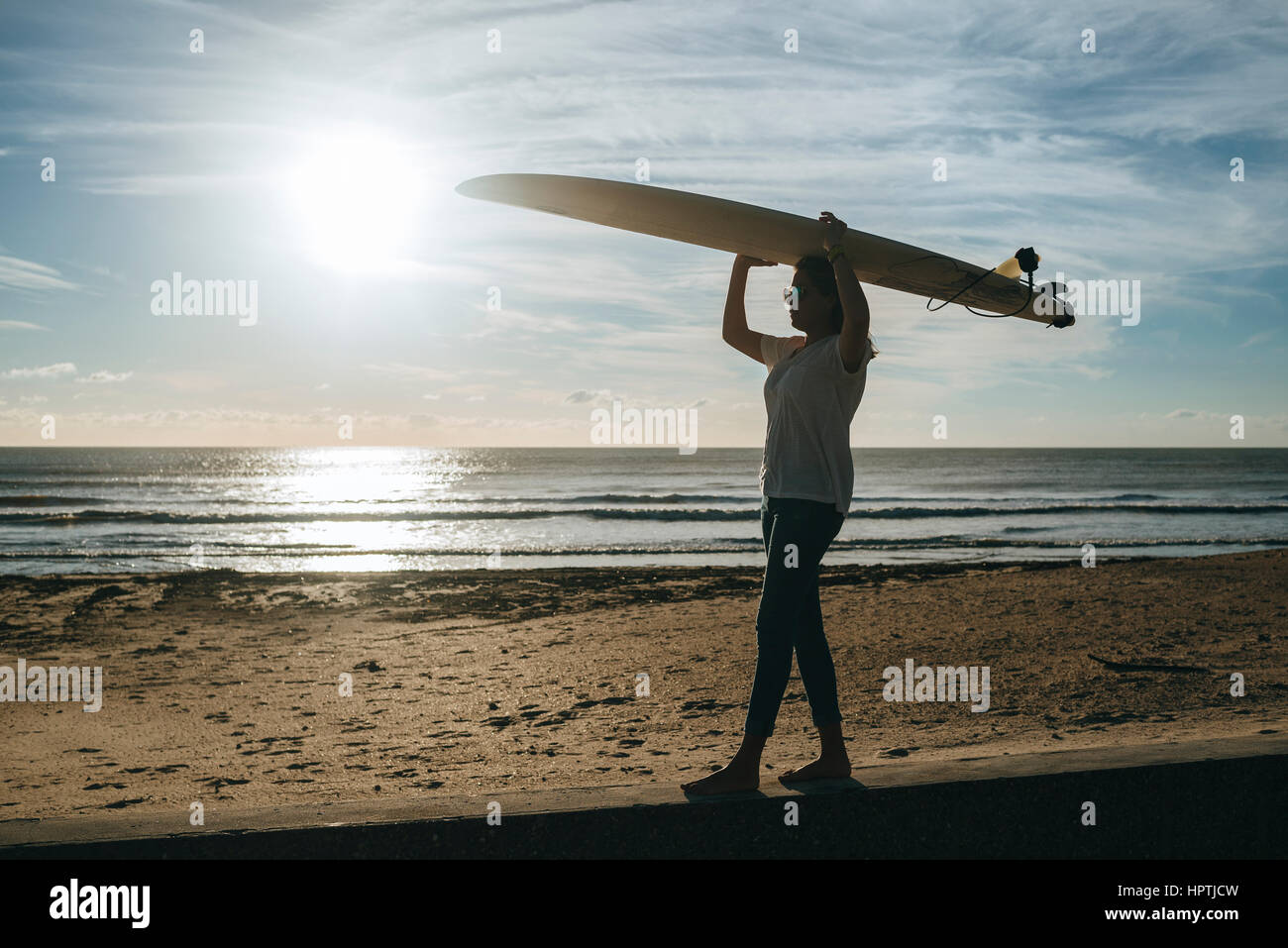 Young woman carrying surfboard head on the beach Stock Photo - Alamy