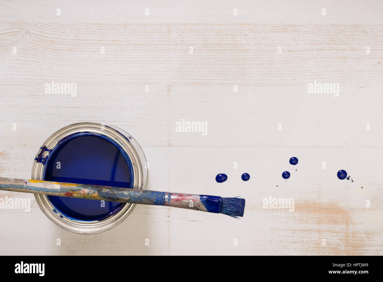 Used paint brush on paint tin with blue varnish Stock Photo - Alamy