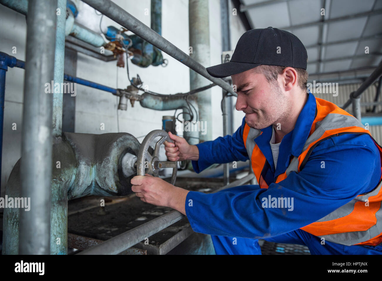 Worker turning valve in factory Stock Photo - Alamy