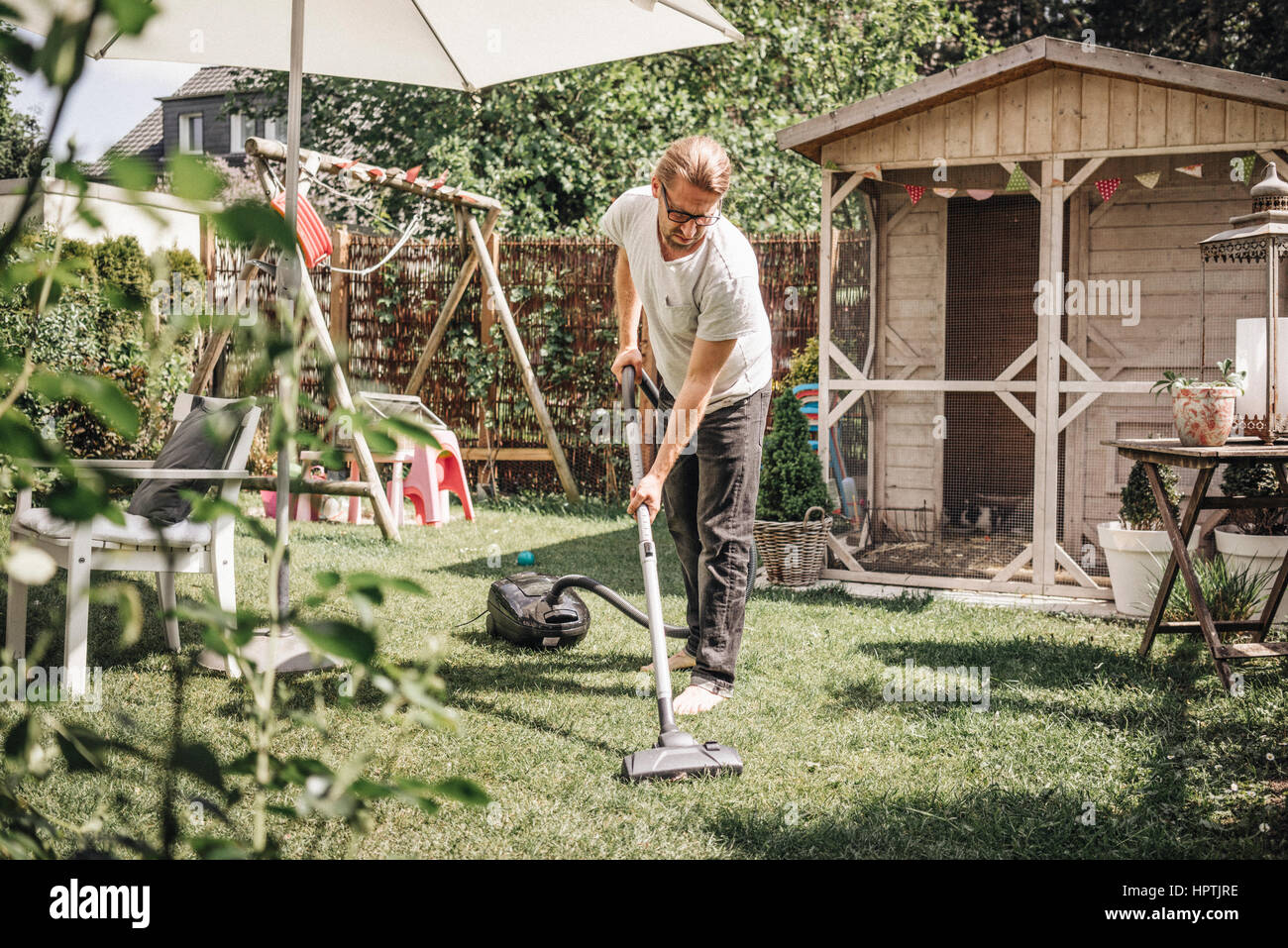 Man hoovering lawn in garden Stock Photo - Alamy