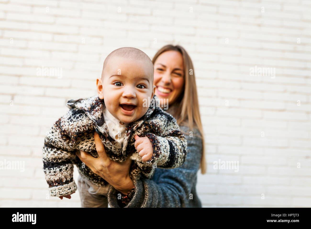 Happy mother with baby at brick wall Stock Photo - Alamy