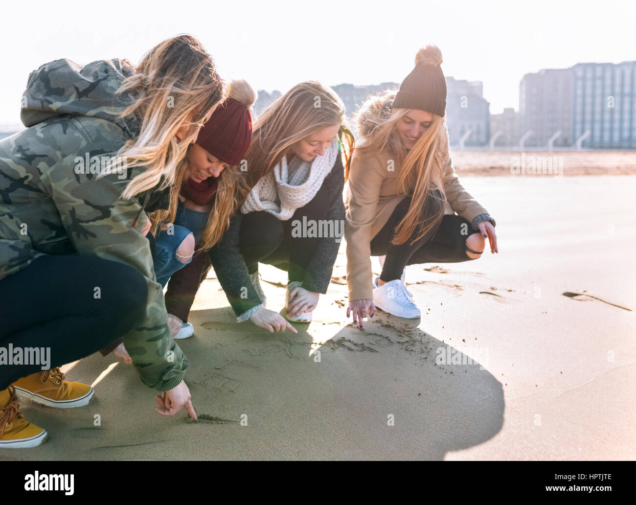 Four friends drawing in the sand on the beach Stock Photo - Alamy