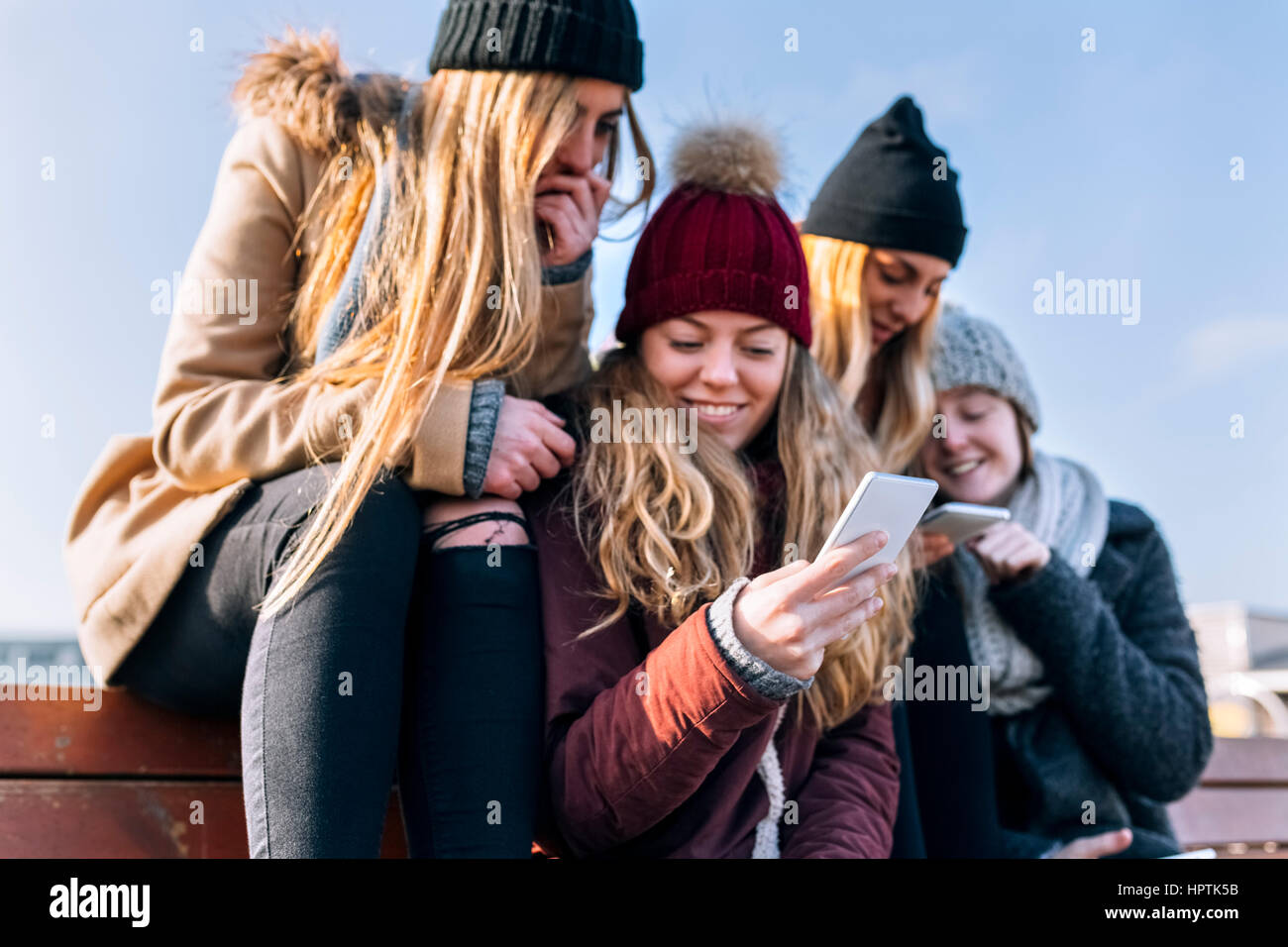 Four friends looking at cell phones Stock Photo - Alamy