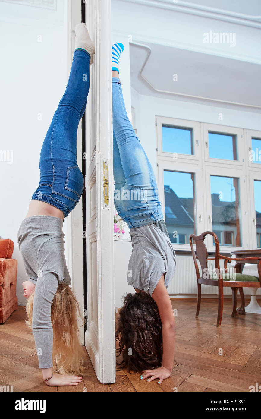 Two girls doing a handstand on opposite sides of a door Stock Photo - Alamy