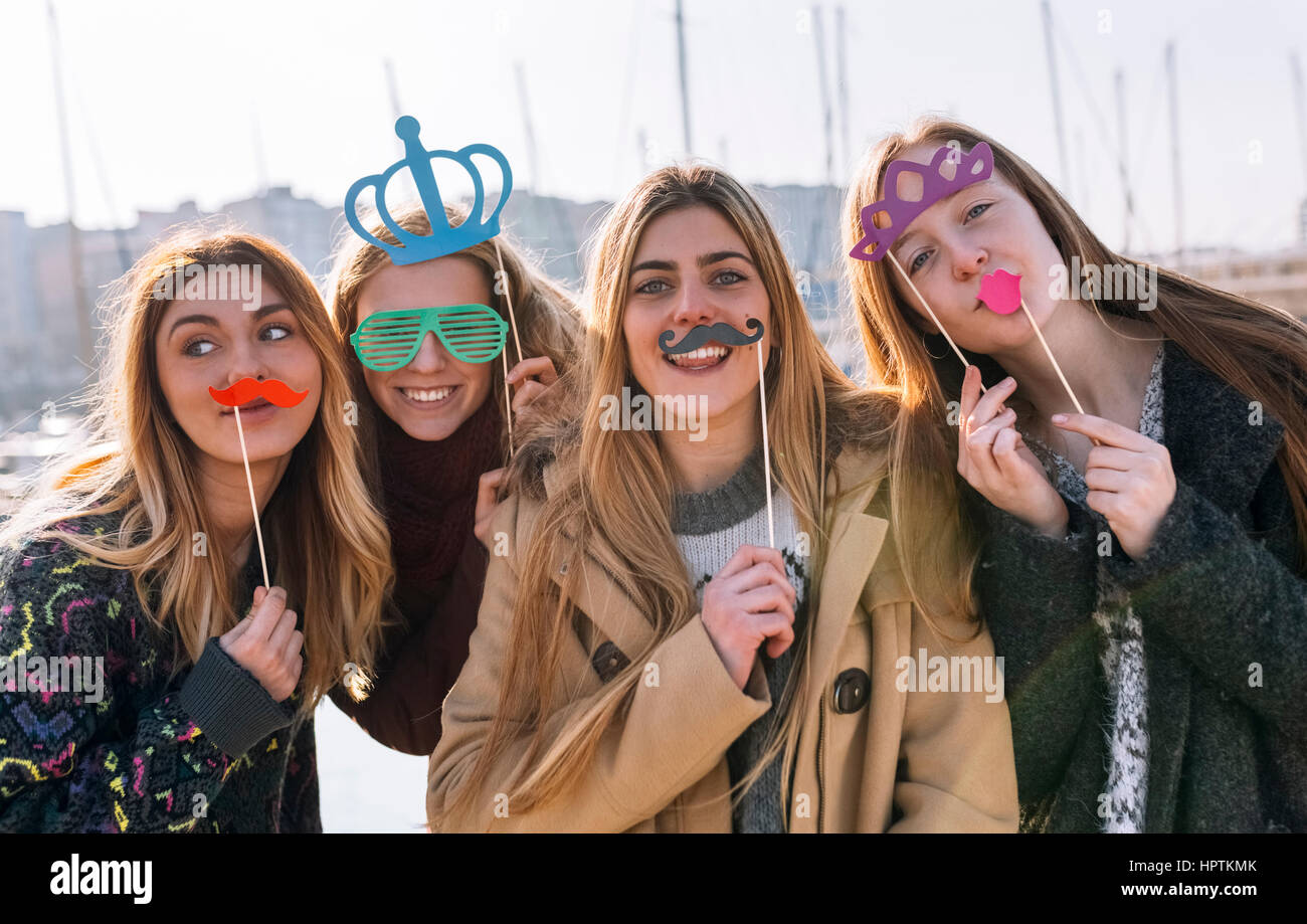 Group picture of four friends with toy moustaches, sunglasses and ...