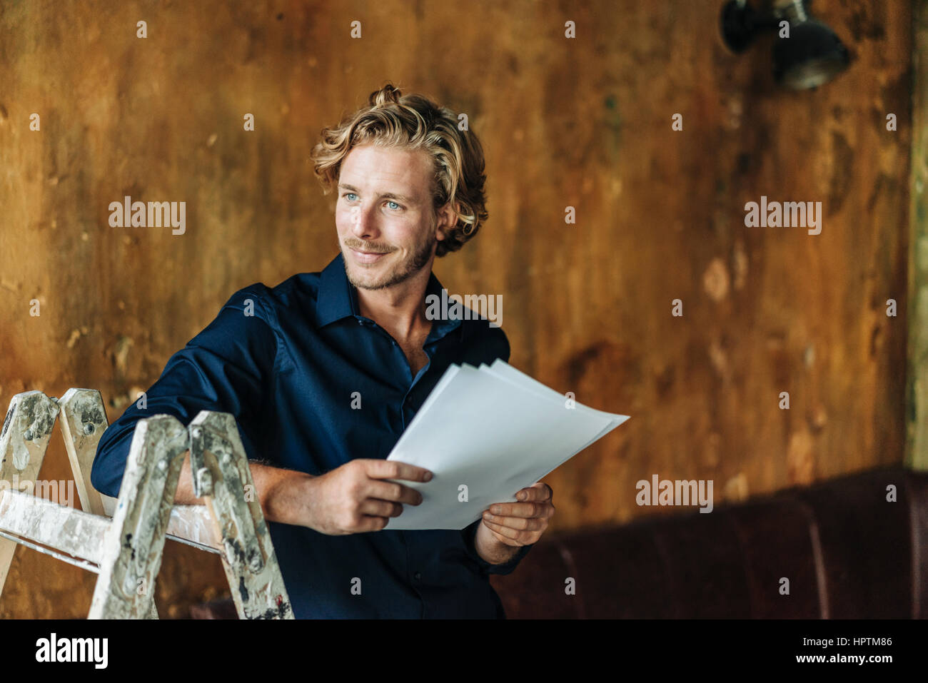 Smiling man leaning on ladder in unfinished room Stock Photo - Alamy