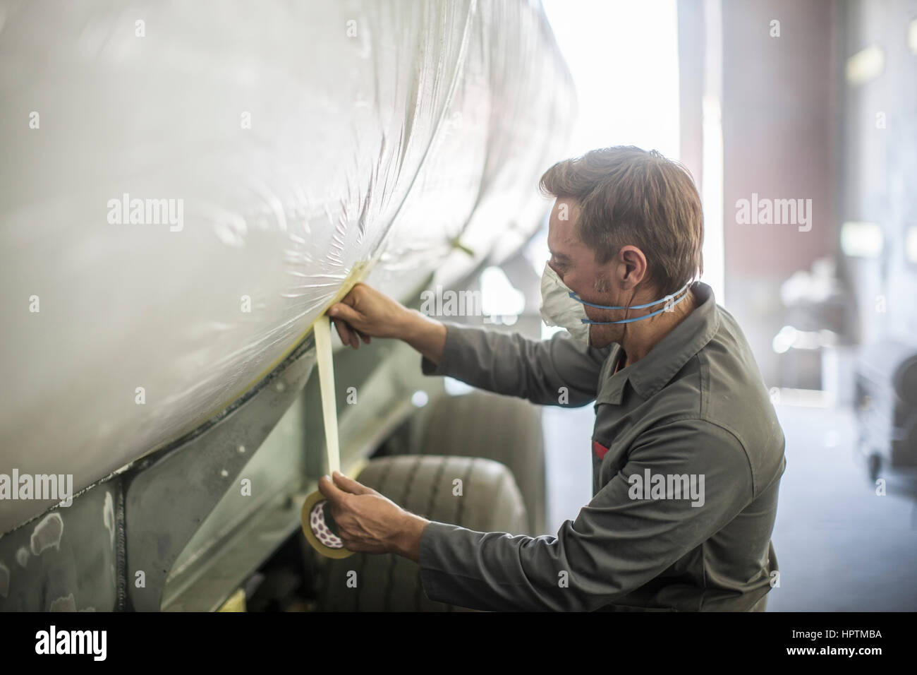 Factory worker in truck manufacture masking container for spray ...