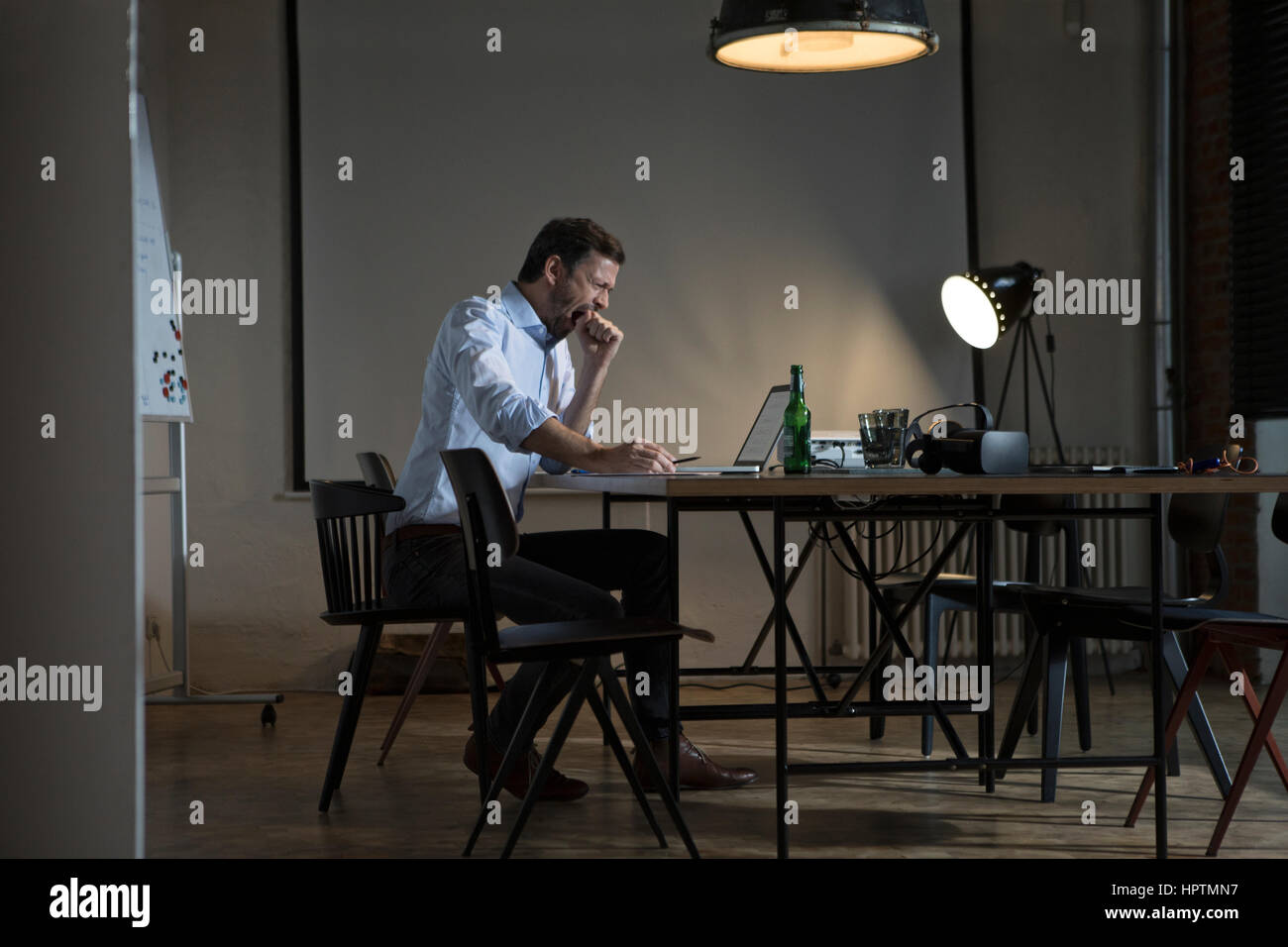 Exhausted businessman working late in office Stock Photo - Alamy