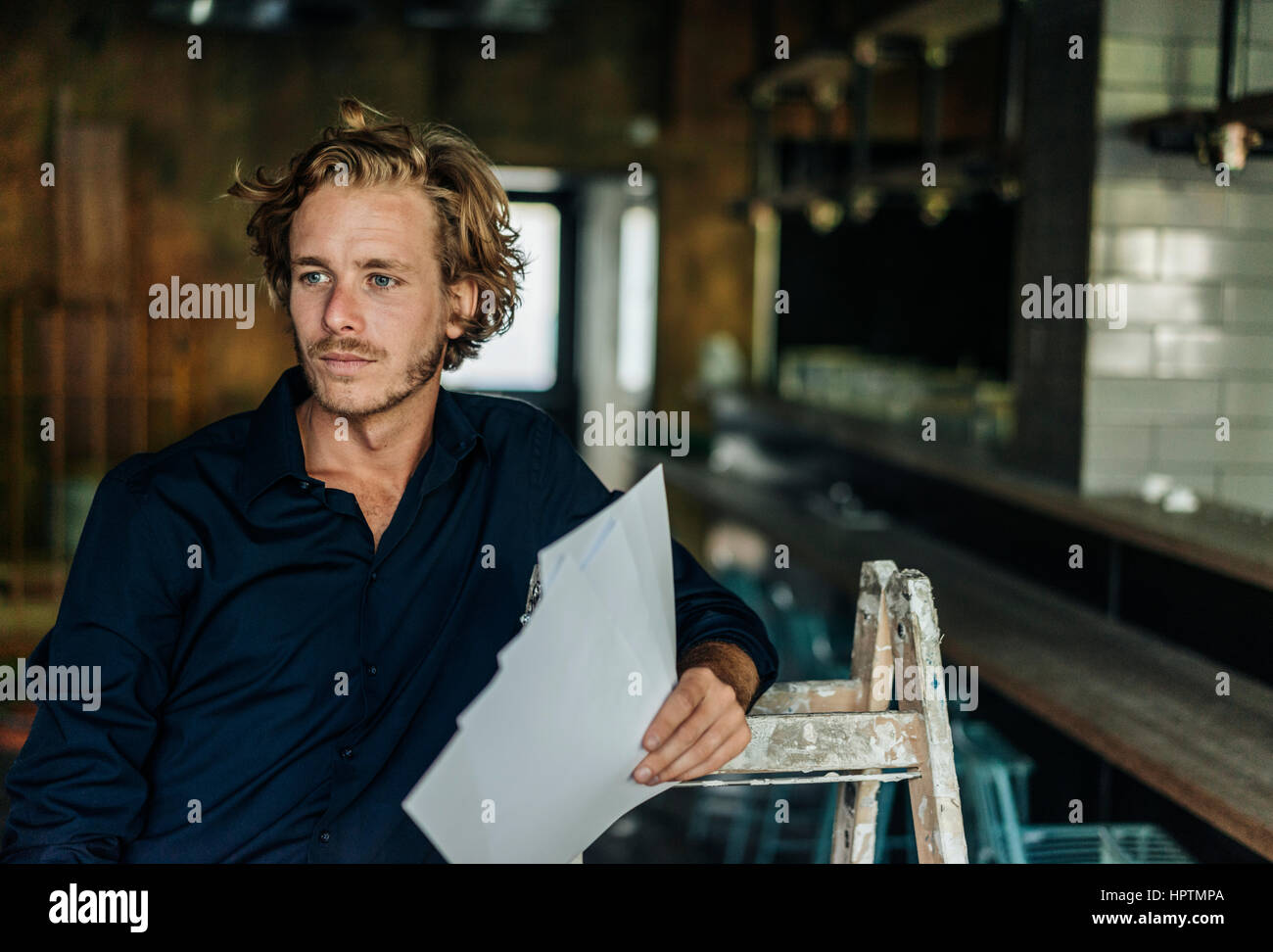 Man leaning on ladder in unfinished room Stock Photo - Alamy