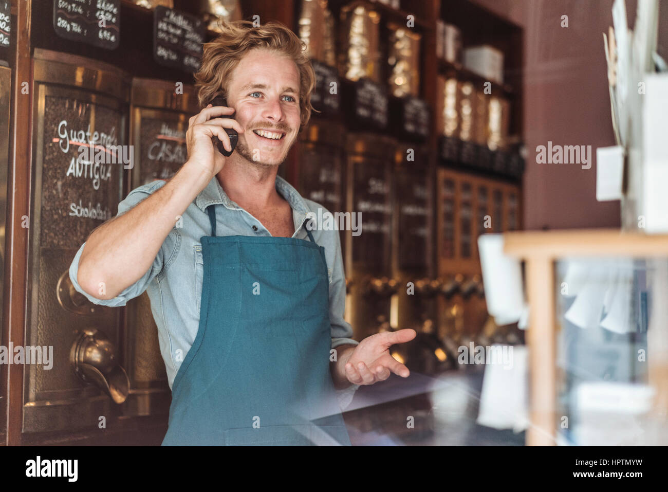 Smiling coffee roaster in his shop on the phone Stock Photo - Alamy