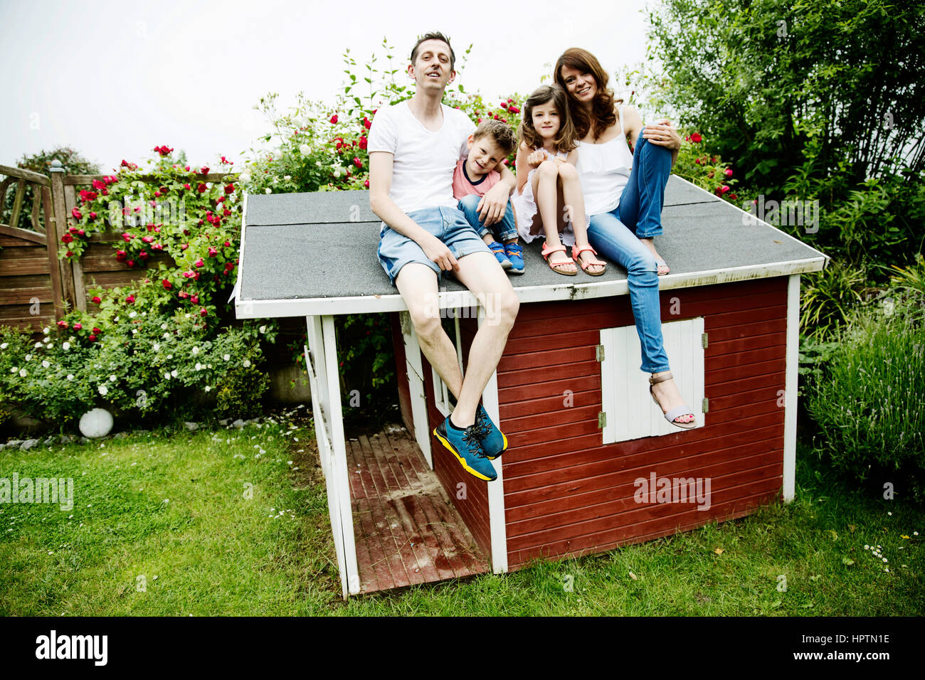 Happy family sitting on roof of their garden shed Stock Photo - Alamy