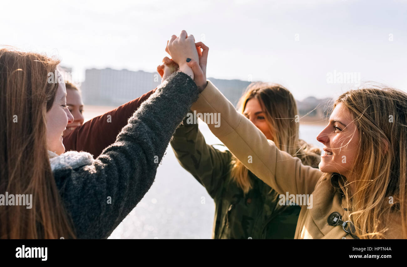 Four happy friends raising their hands together Stock Photo - Alamy