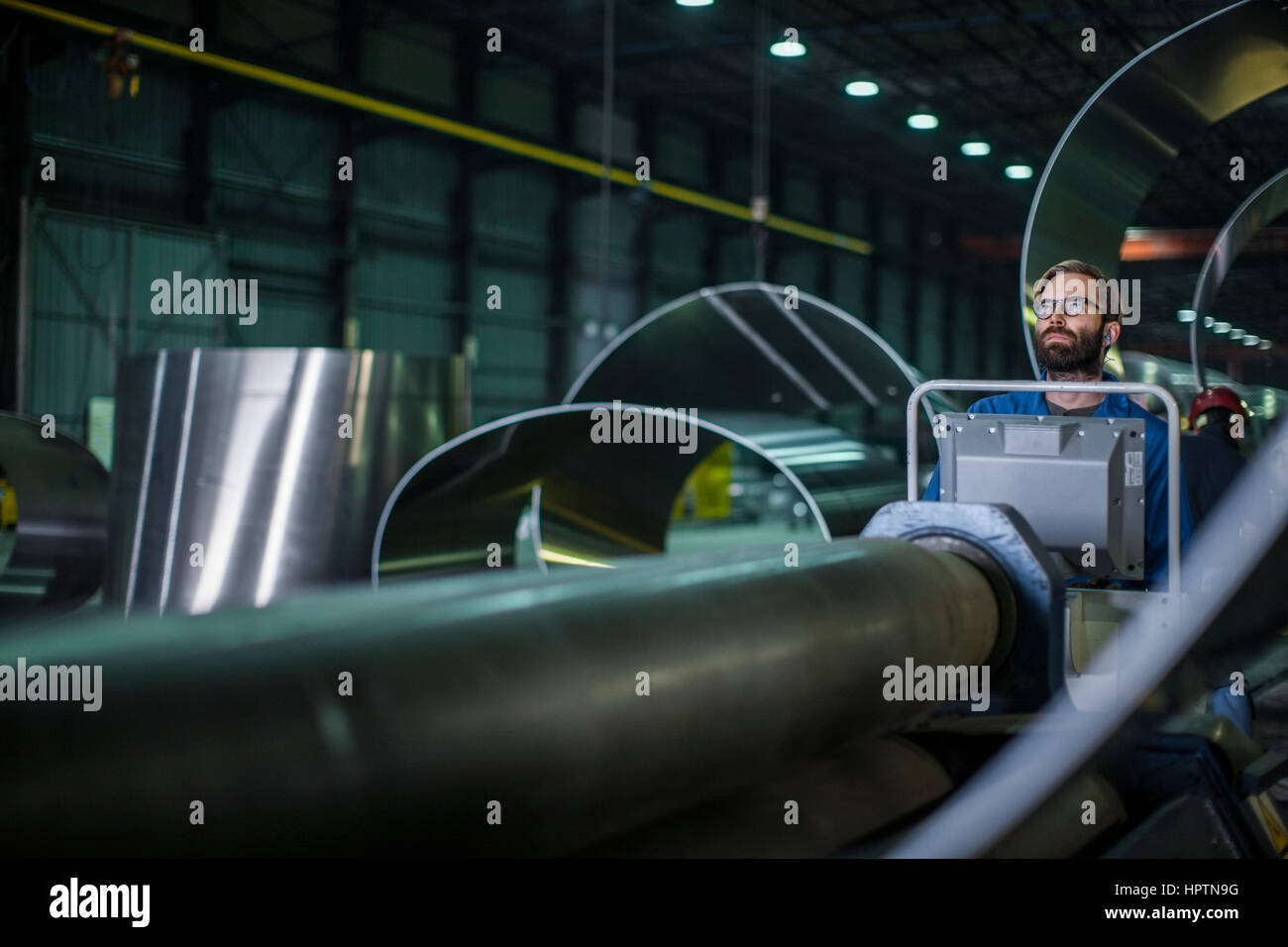Worker operating machinery at control panel in steel factory Stock ...