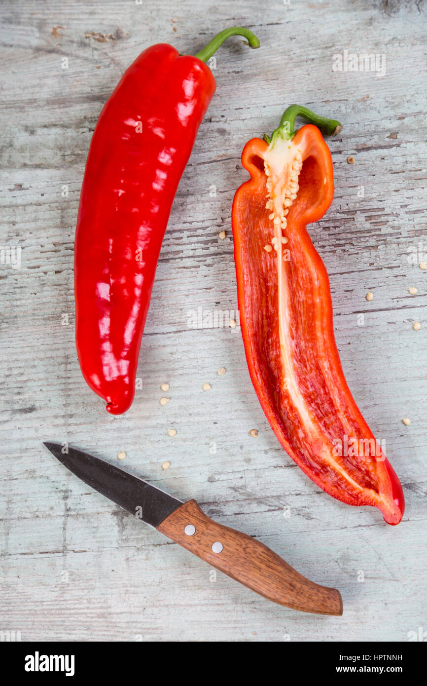 Whole and sliced red pointed pepper and a kitchen knife on wood Stock ...