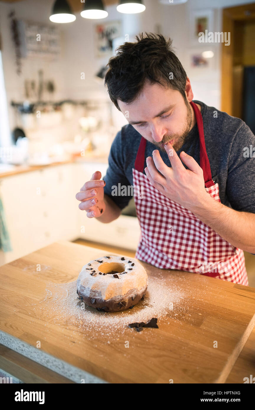 Man standing in kitchen garnishing ring cake Stock Photo - Alamy