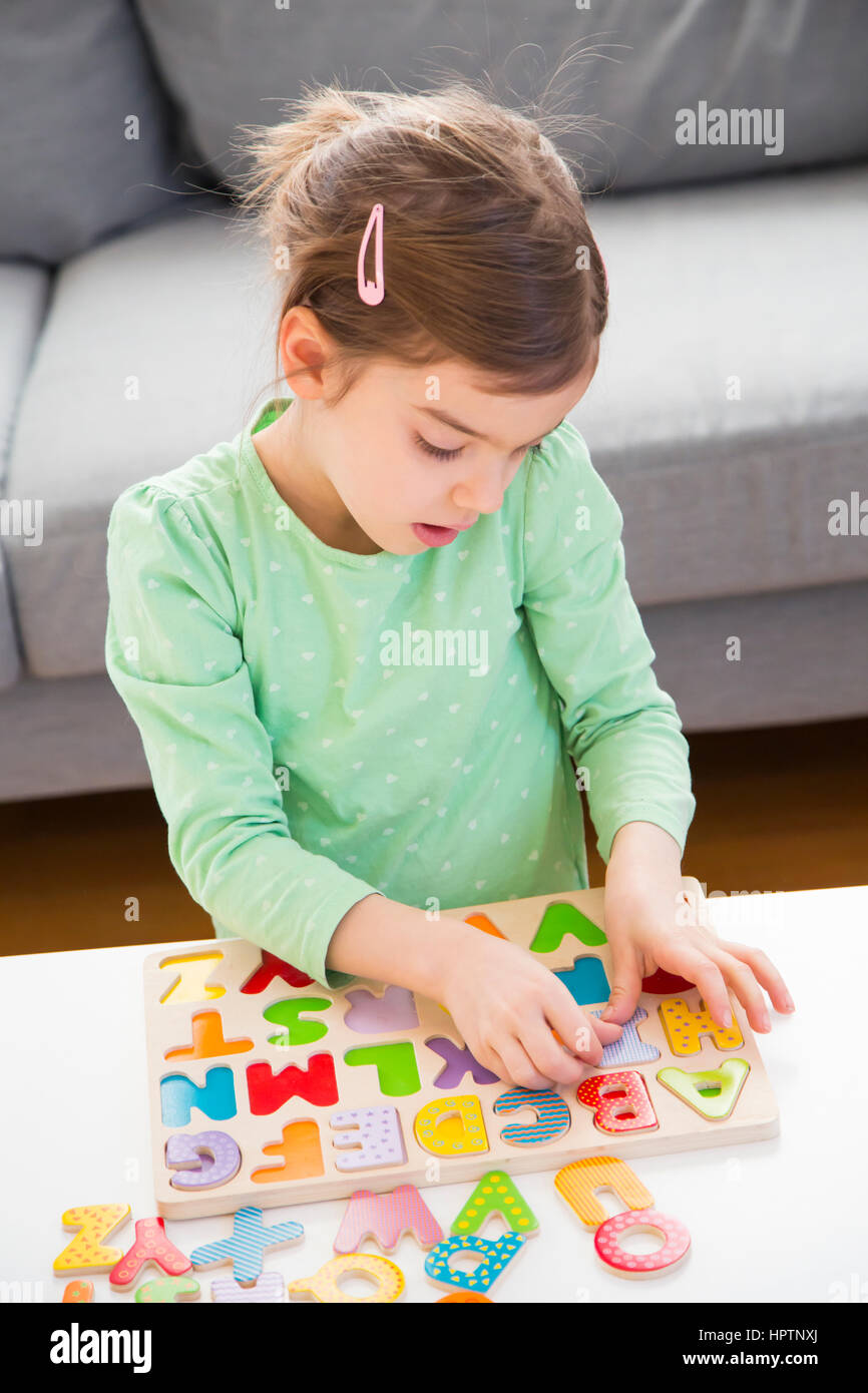 Little girl learning alphabet with wooden letters at home Stock Photo ...