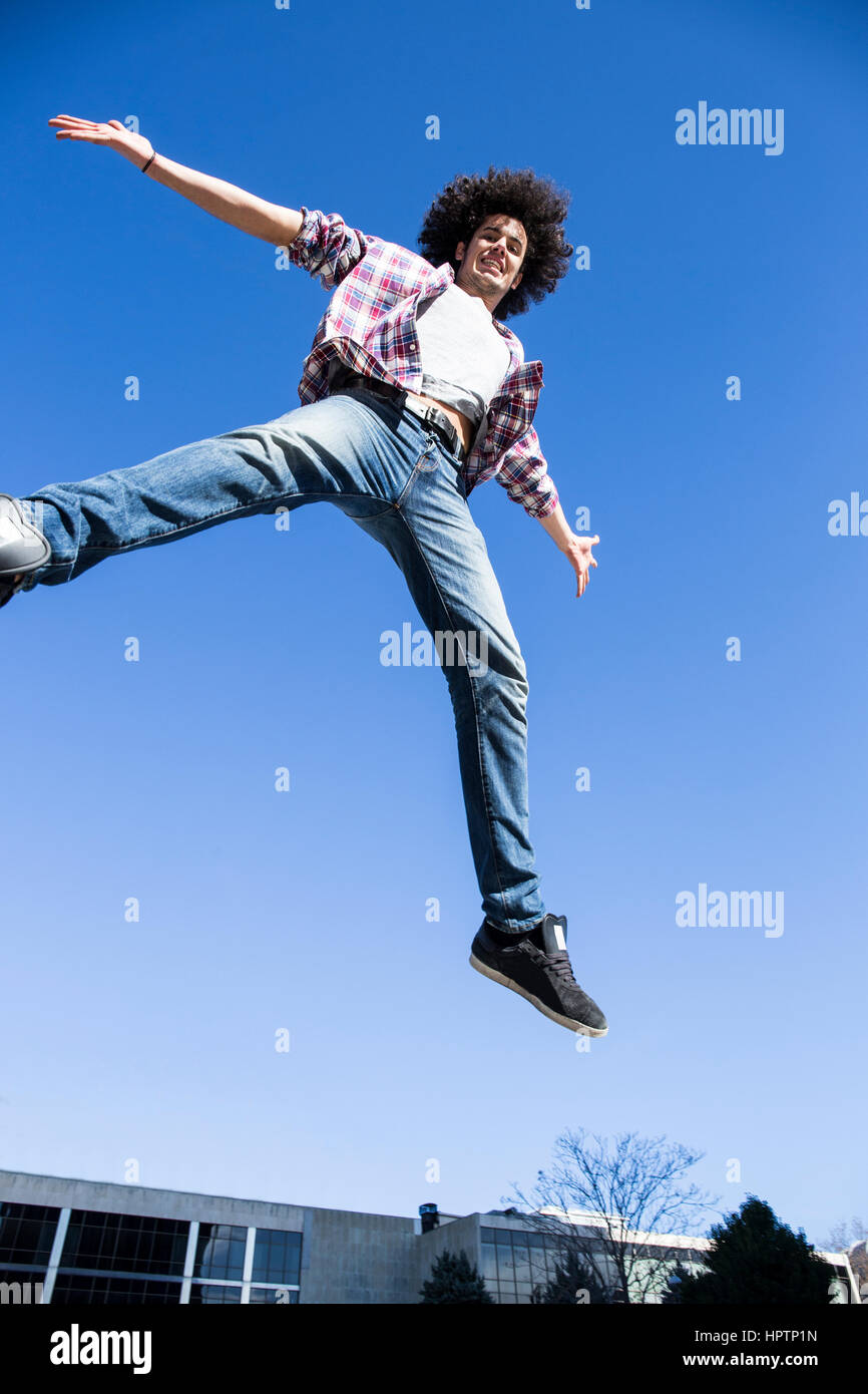 Smiling young man jumping in the air with arms outstretched Stock Photo ...