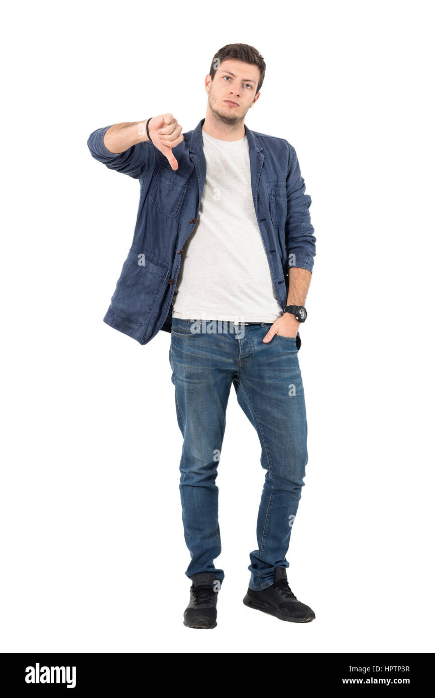 Disappointed young man in jeans showing thumbs down gesture at camera ...