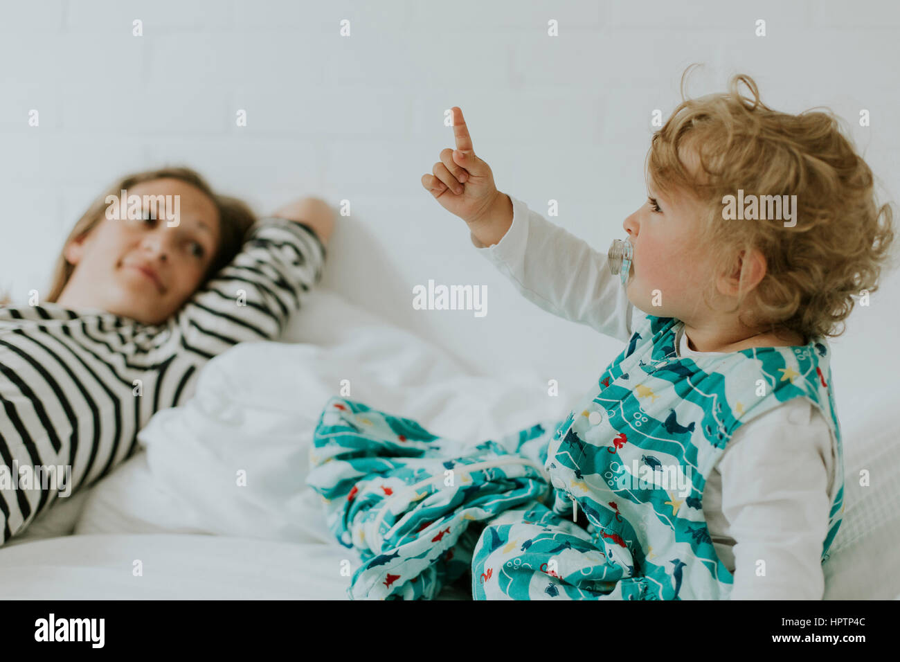 Little girl with mother in bed pointing her finger Stock Photo - Alamy