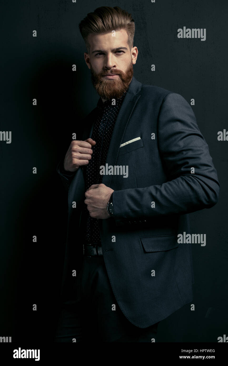Stylish handsome bearded man in trendy suit posing on black Stock Photo ...