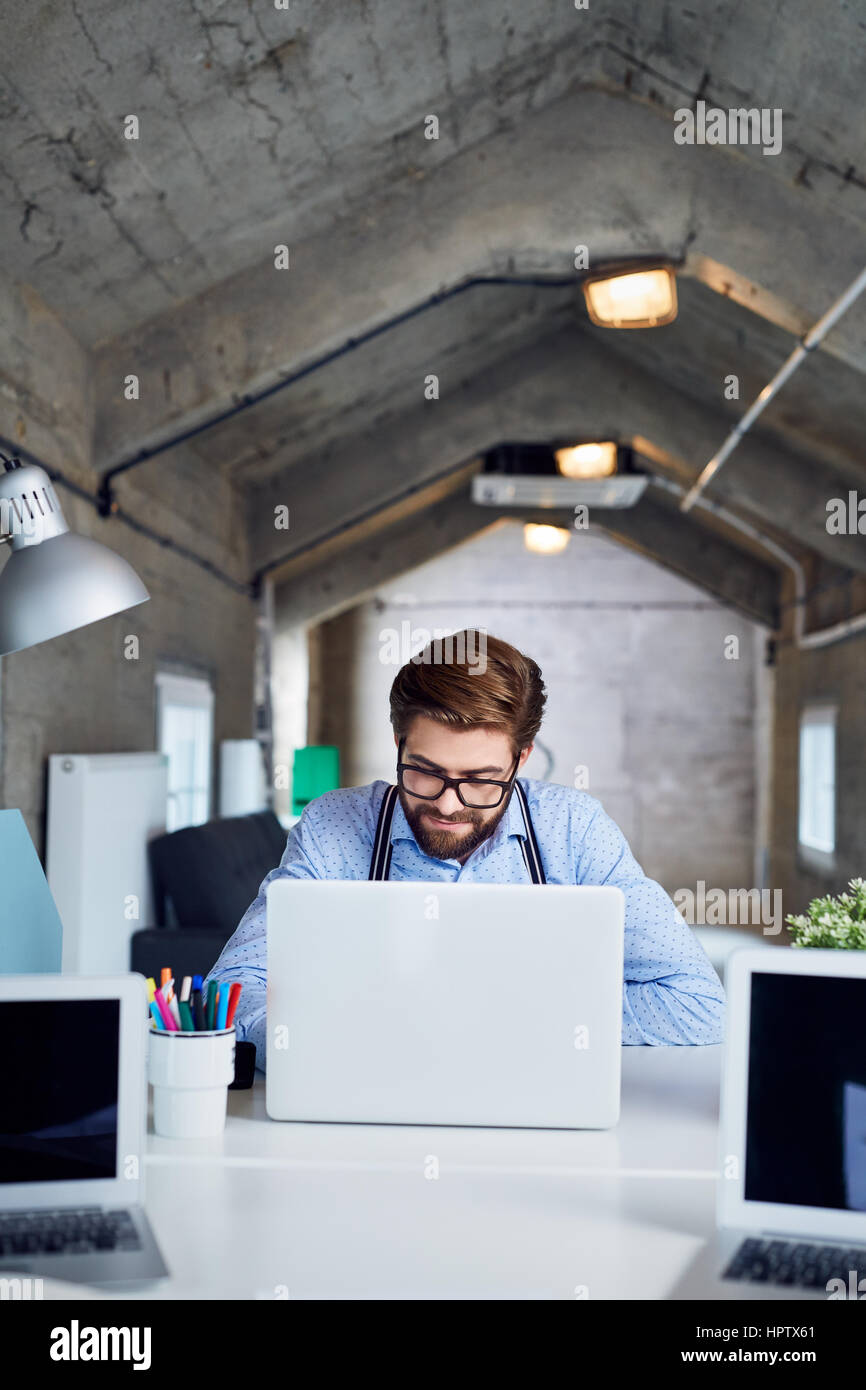 Designer working on laptop at creative agency office Stock Photo - Alamy