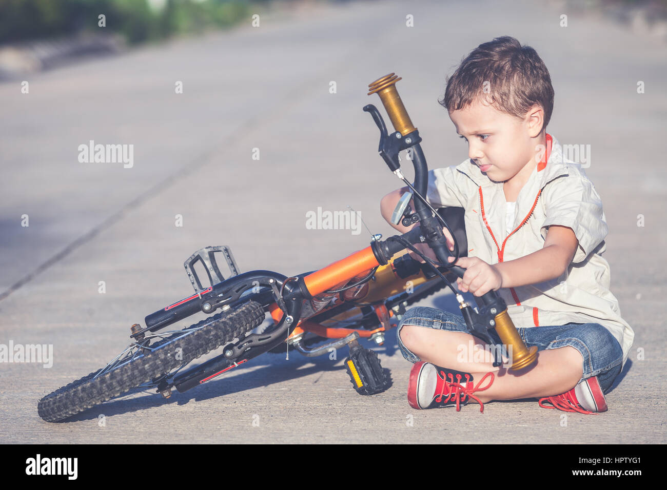 Happy little boy with bicycle sitting on road at the day time Stock ...