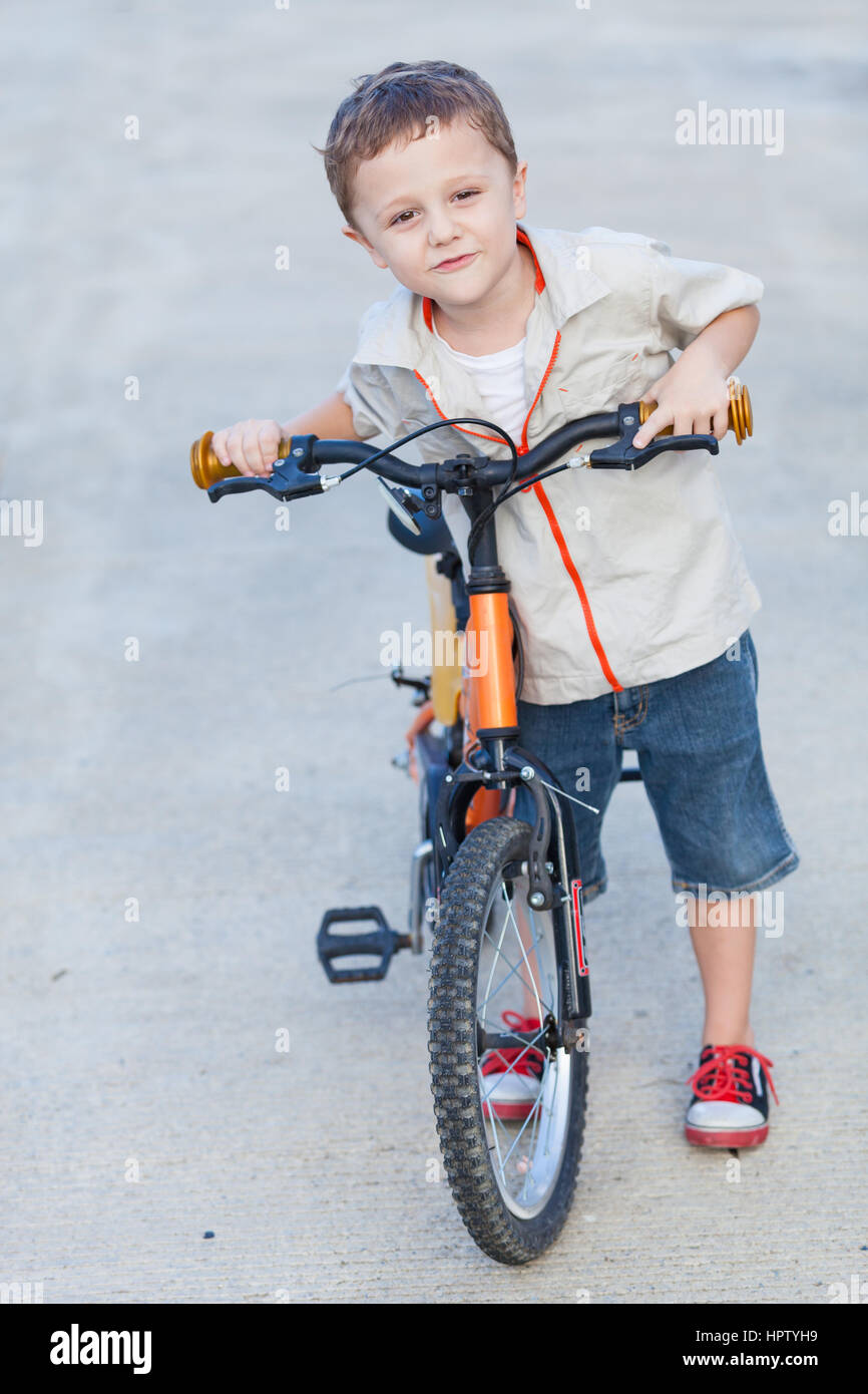 Happy little boy with bicycle standing on road at the day time Stock ...
