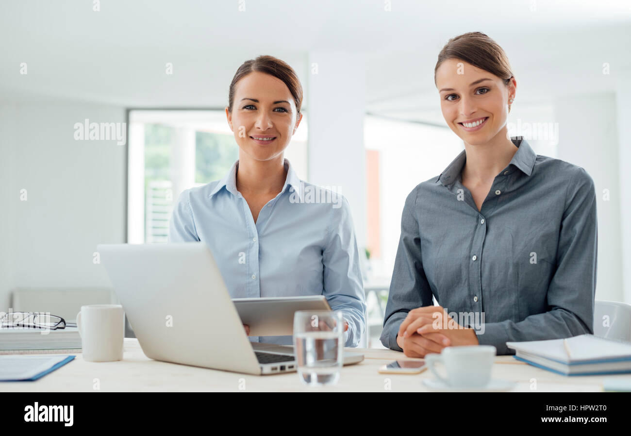 Professional business women sitting at office desk and working together ...