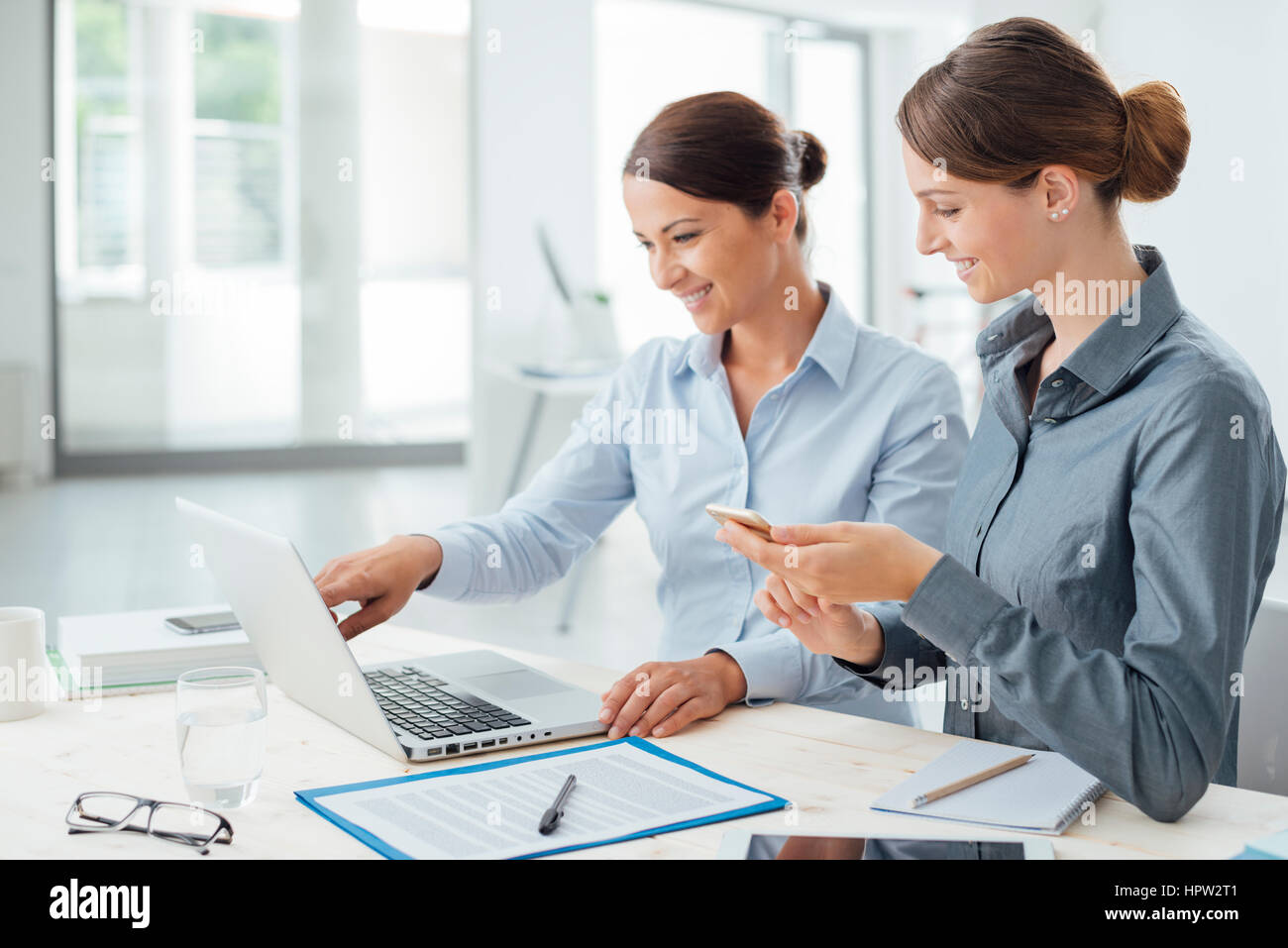 Business women at office desk working together on a laptop, teamwork ...