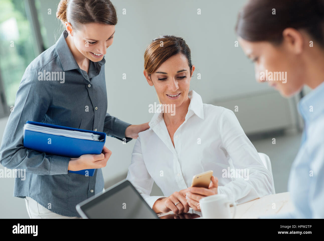 Female office workers talking and watching a mobile phone screen, woman ...