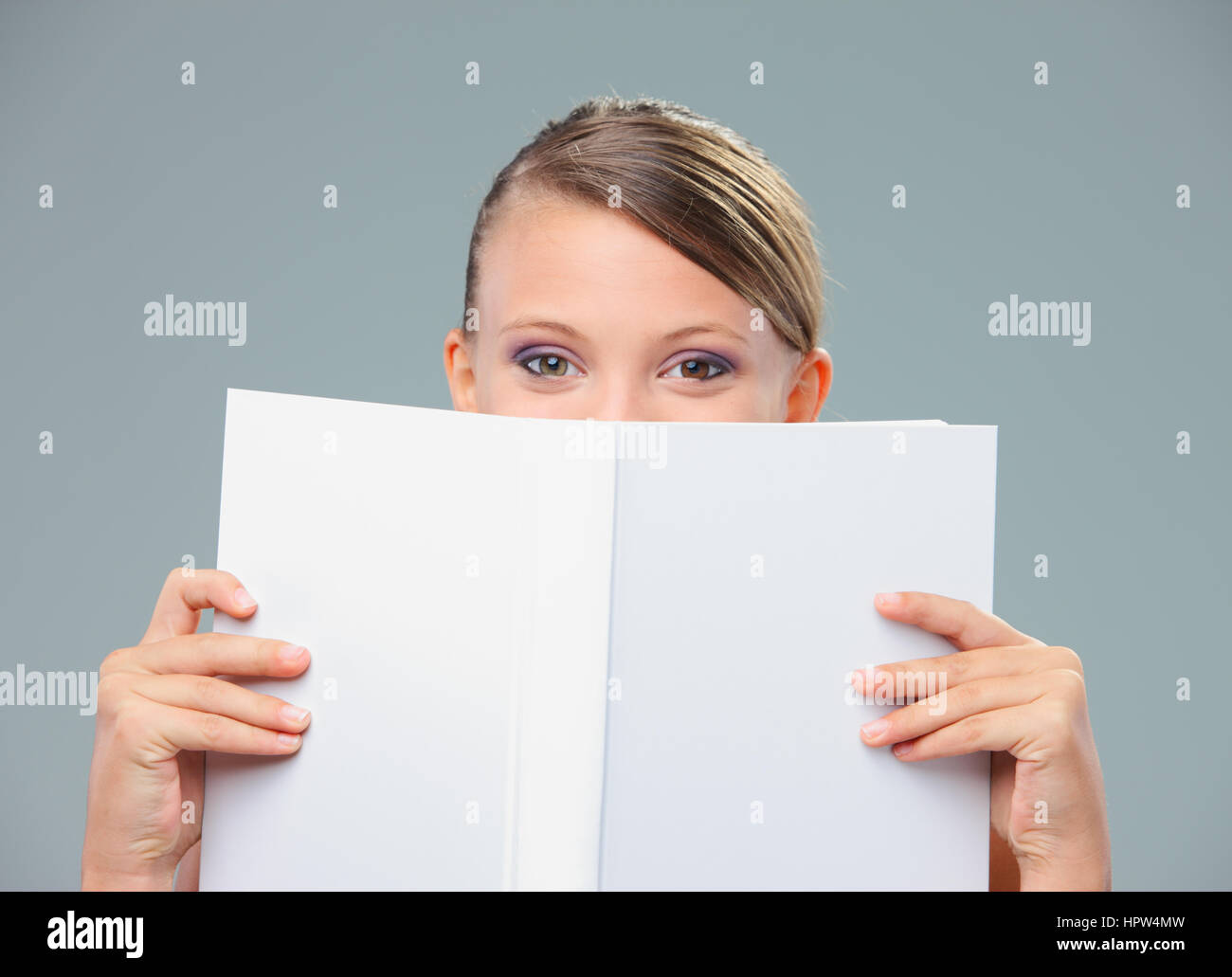 Beautiful young woman hiding herself behind a book Stock Photo - Alamy