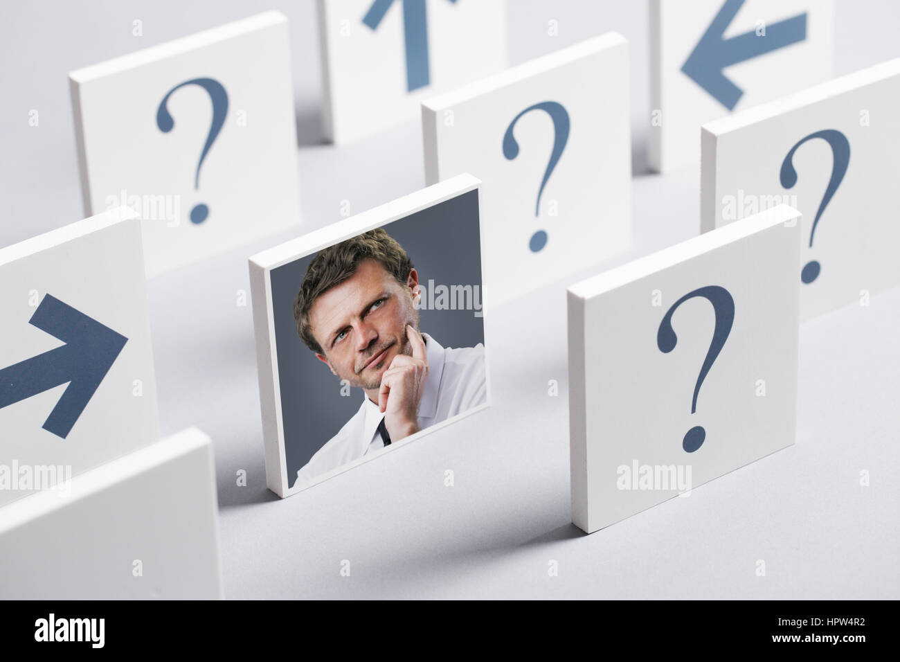 Portrait of a confused businessman surrounded by question marks and ...