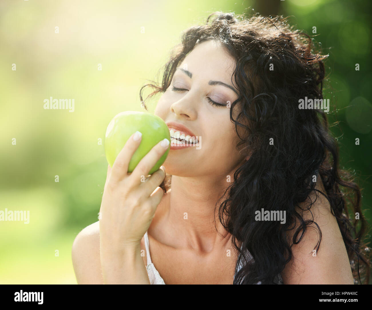 Beautiful cheerful woman eating a green apple, outdoors portrait Stock ...