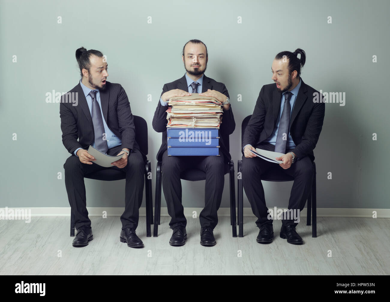 Businessman with a huge resume sitting in line with other candidates at ...