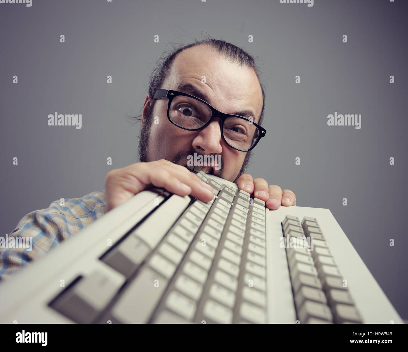 Eccentric angry man bites a keyboard Stock Photo - Alamy