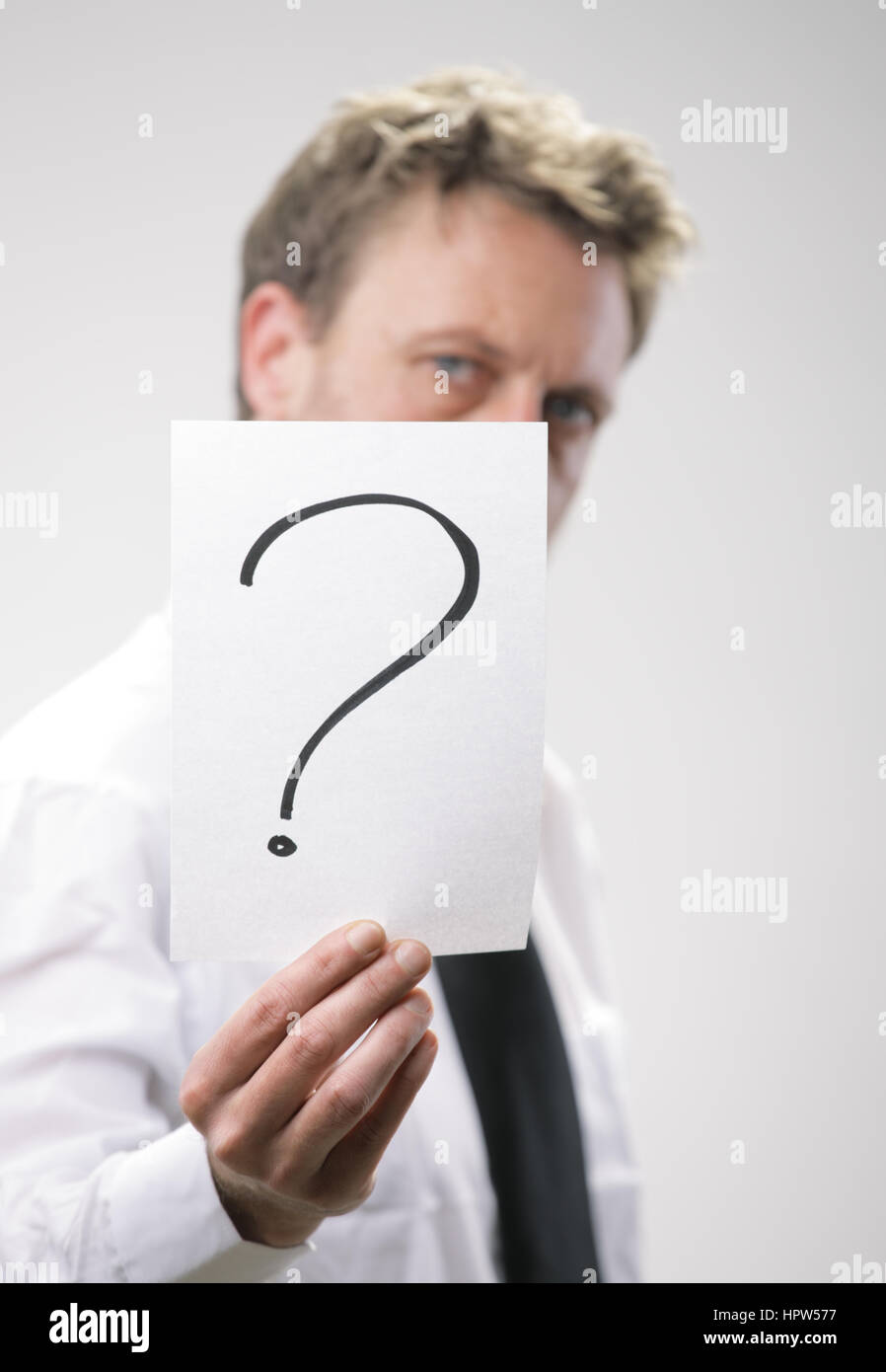 Mature businessman holding a marked placard with a question mark on it ...