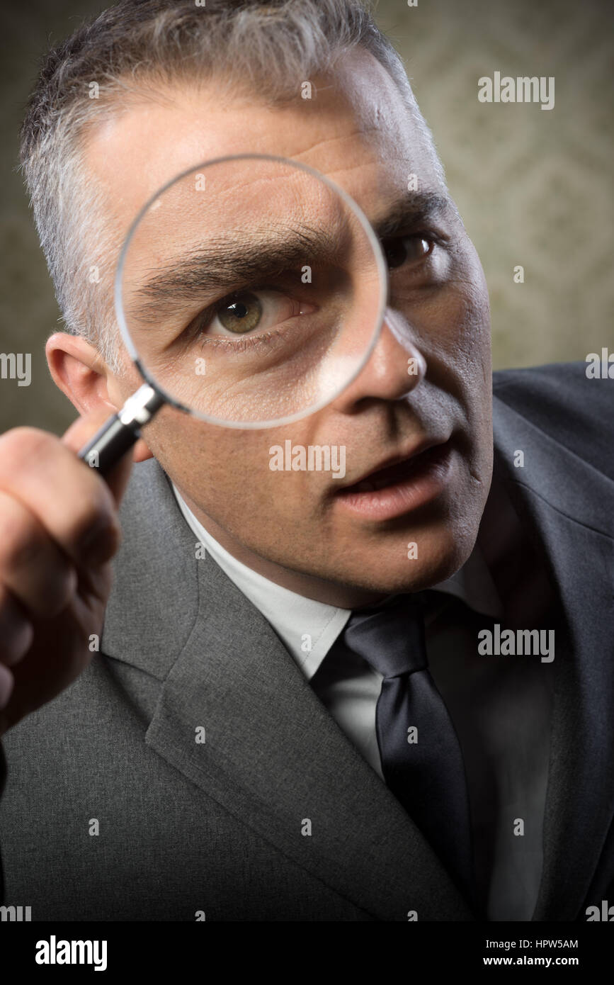 Vintage detective looking at camera through magnifying glass Stock ...