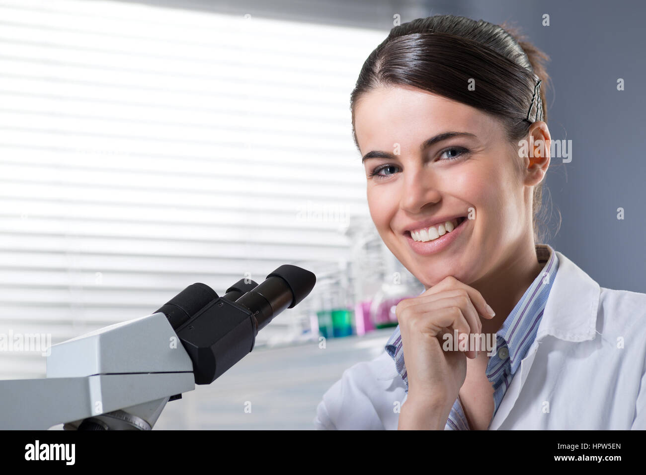 Confident female researcher in the chemistry lab with microscope and ...