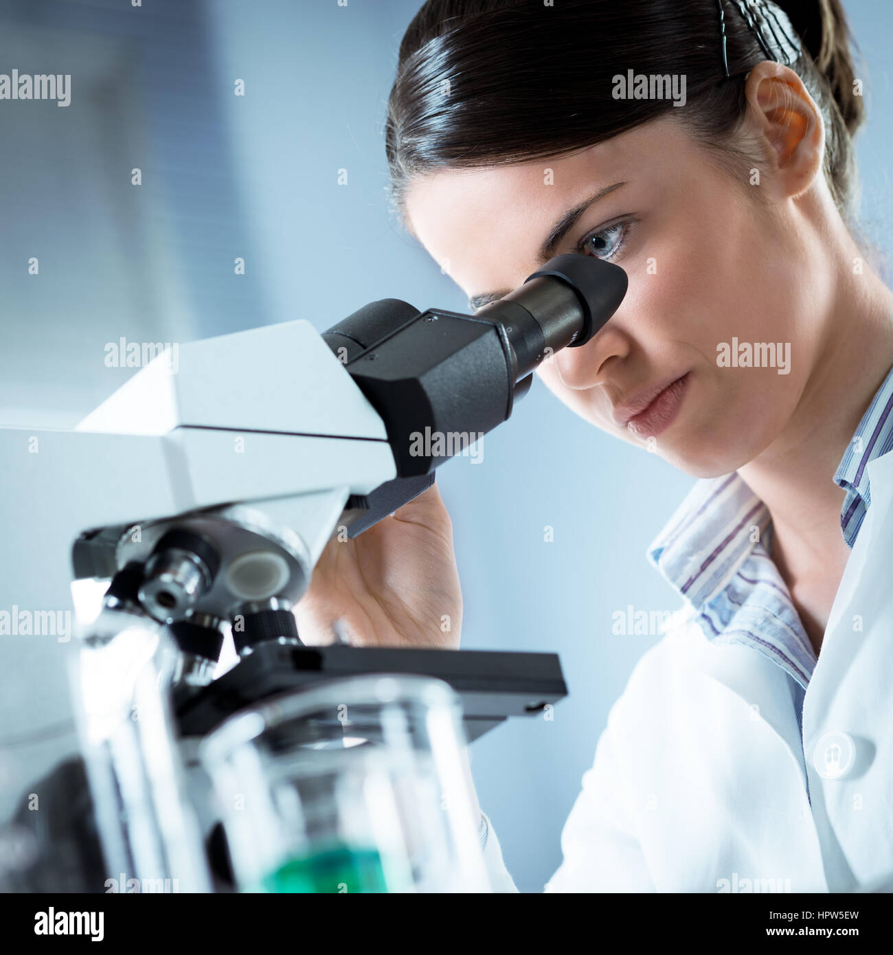 Female researcher analyzing samples with microscope in the laboratory ...