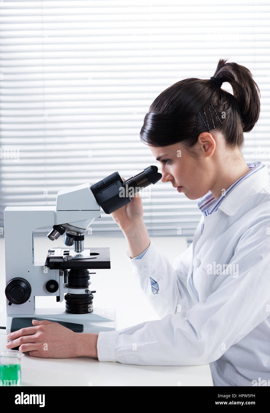 Female researcher analyzing samples with microscope in the laboratory ...