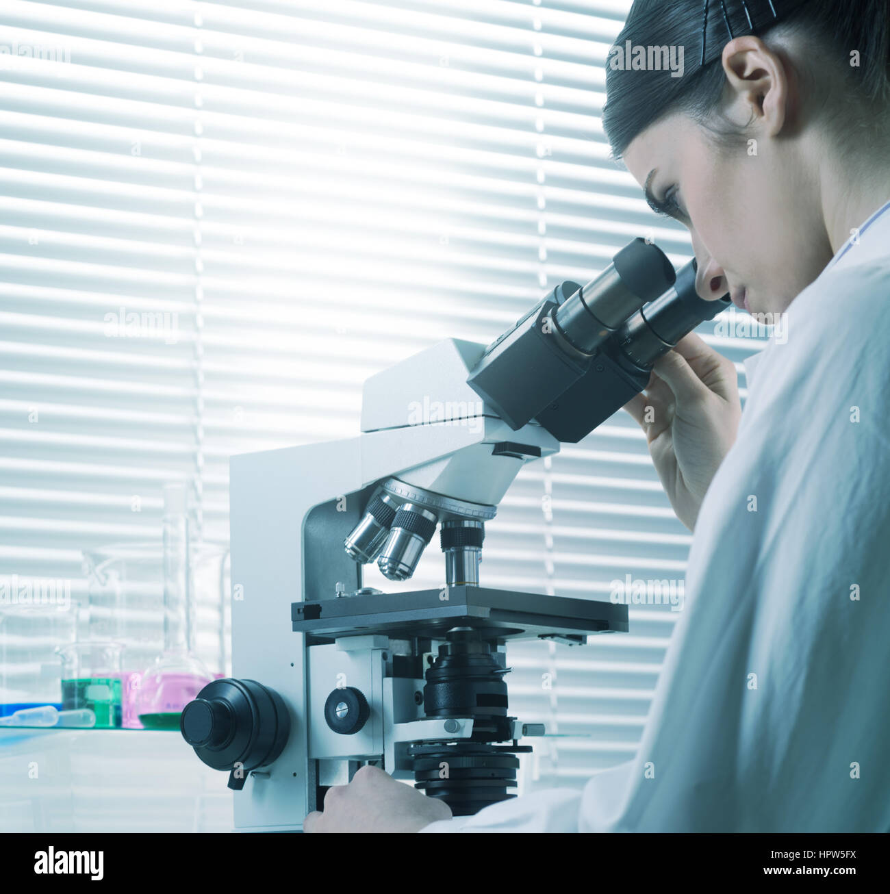 Young female researcher using microscope in the chemistry lab with ...