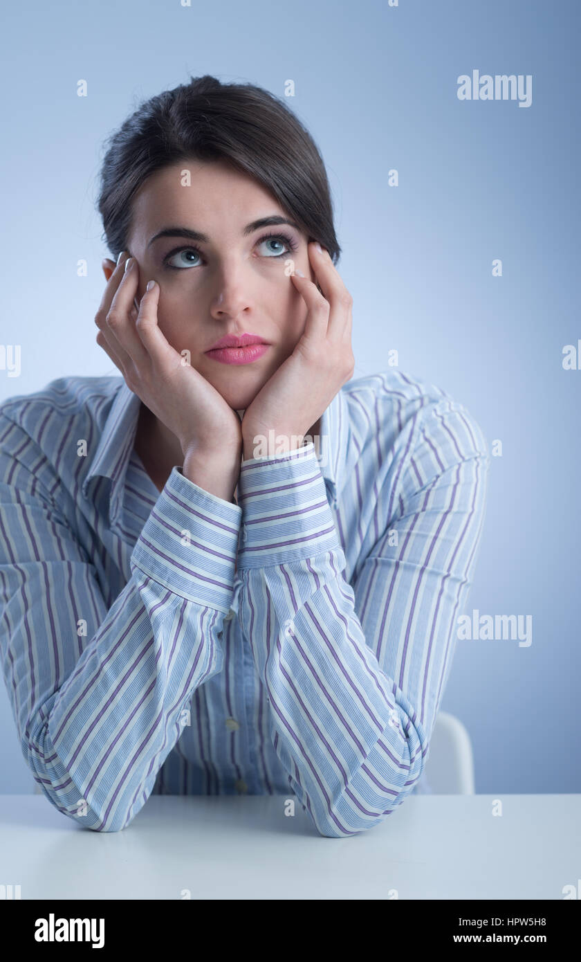 Pensive young woman at desk looking up Stock Photo - Alamy