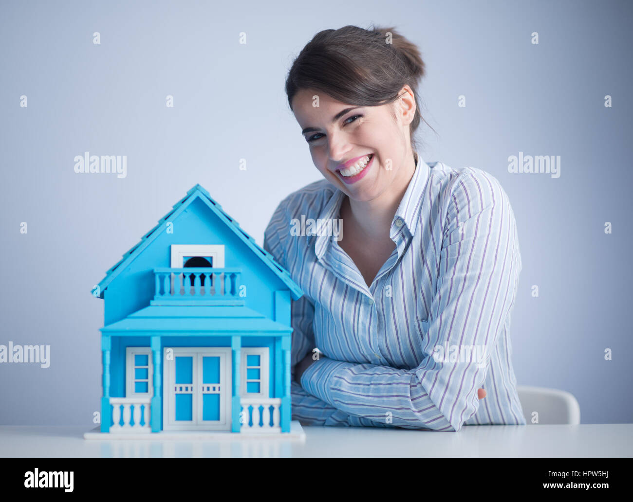 Beautiful woman at desk with light blue model house Stock Photo - Alamy