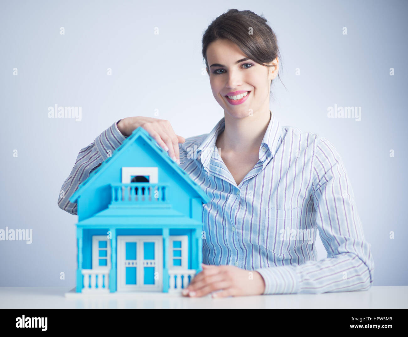 Beautiful woman at desk with light blue model house Stock Photo - Alamy