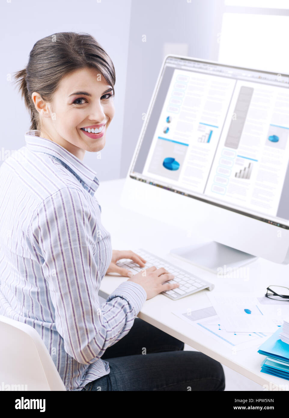 Young office worker smiling and typing on a keyboard at office Stock ...