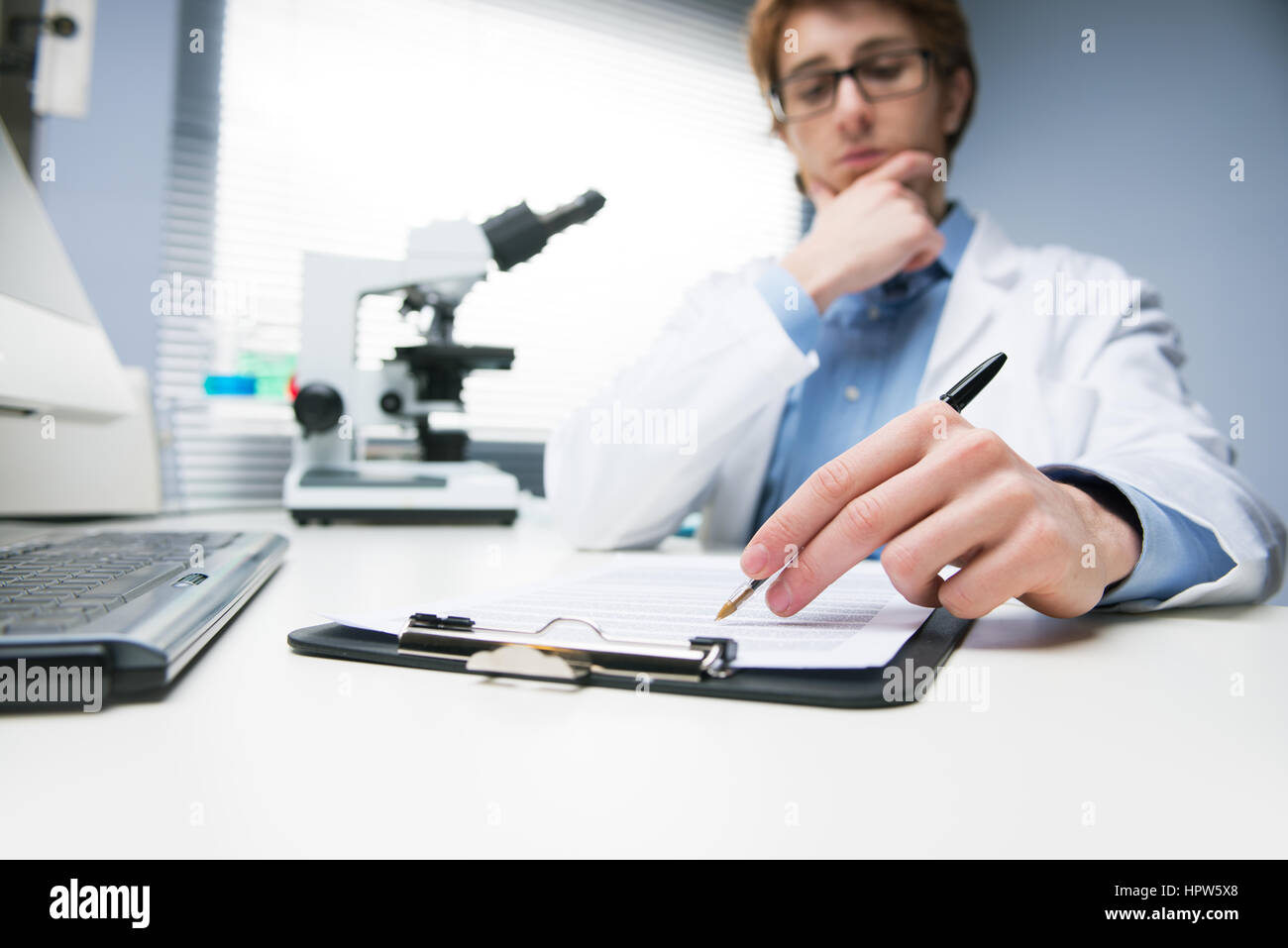 Young researcher writing notes at desk in the chemical lab Stock Photo ...