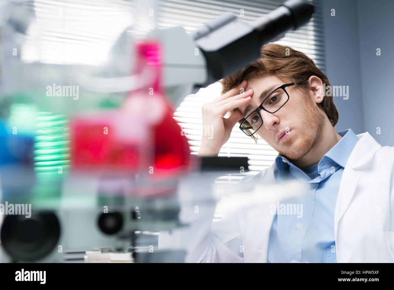 Young researcher at work with laboratory glassware on foreground Stock ...