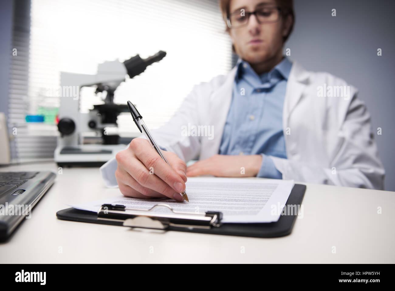 Young researcher writing notes at desk in the chemical lab Stock Photo ...