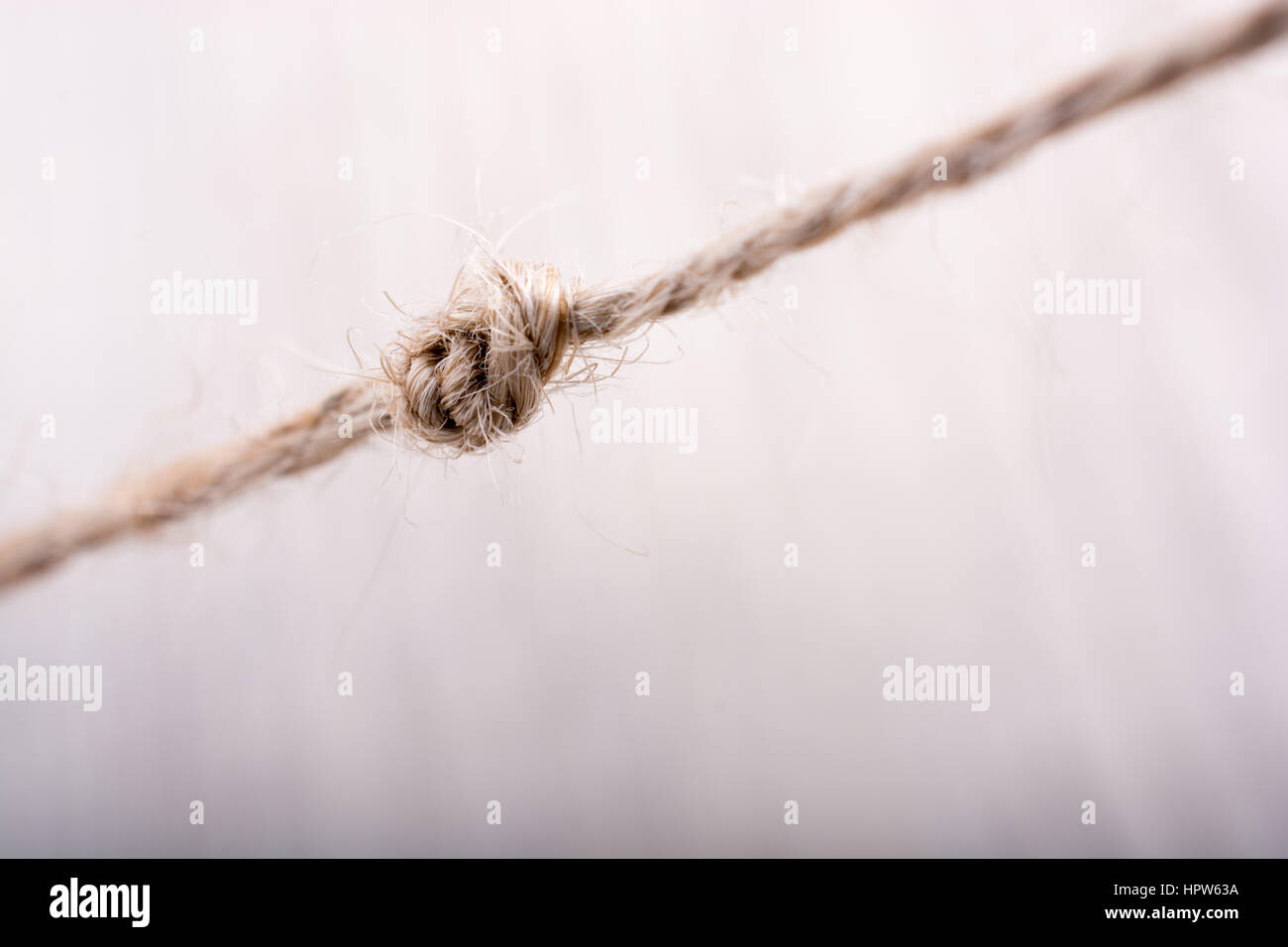 Thread tied as knot on a light color background Stock Photo - Alamy