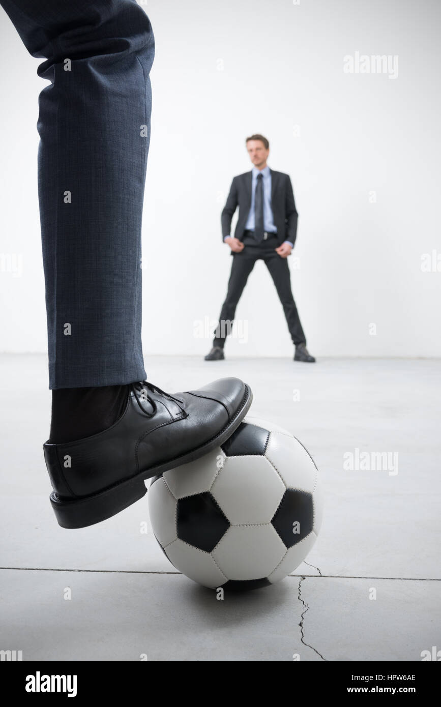 Businessmen playing soccer in an empty room, ball and foot close up ...